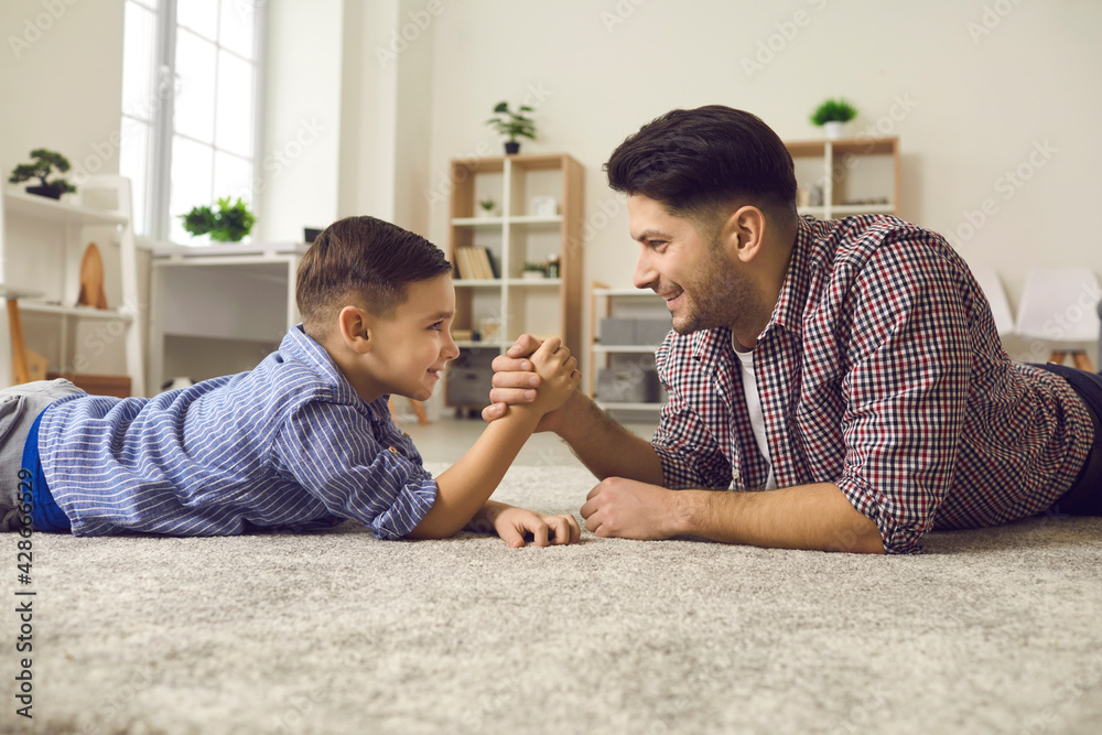 Happy boy and his dad spending time at home and having fun together ...