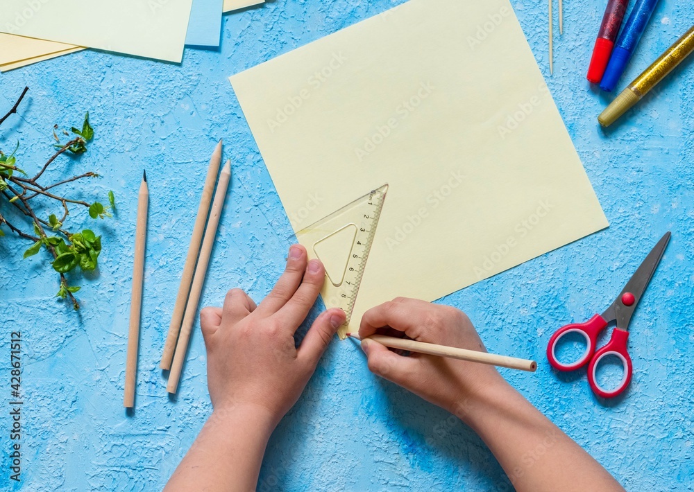 Step-by-step making of a paper weather vane by a child on a blue ...