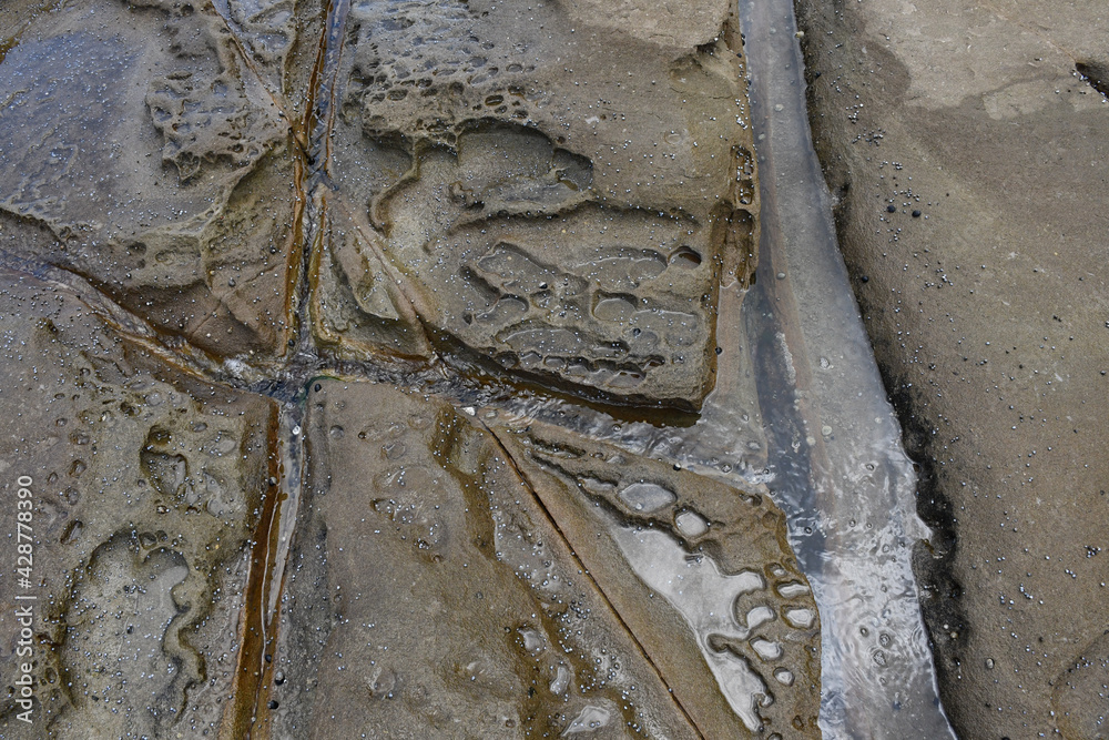 Overhead shot of a flat rock surface with water filling its cracks and ...