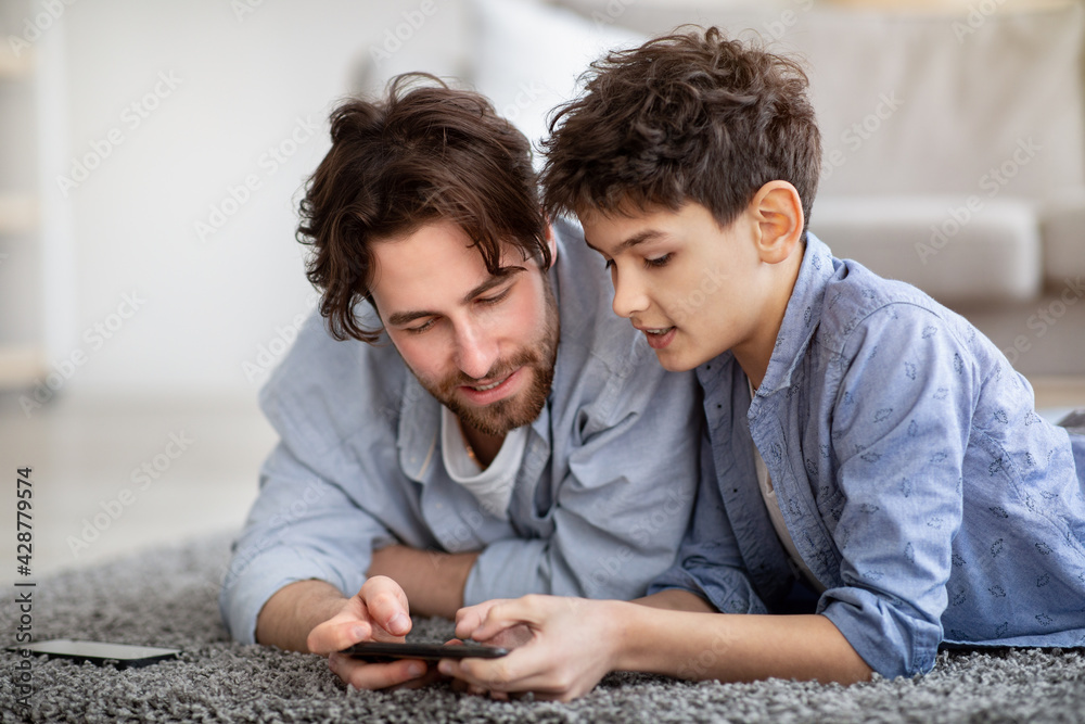 Father and son using smartphone, watching photos or boy helping daddy ...