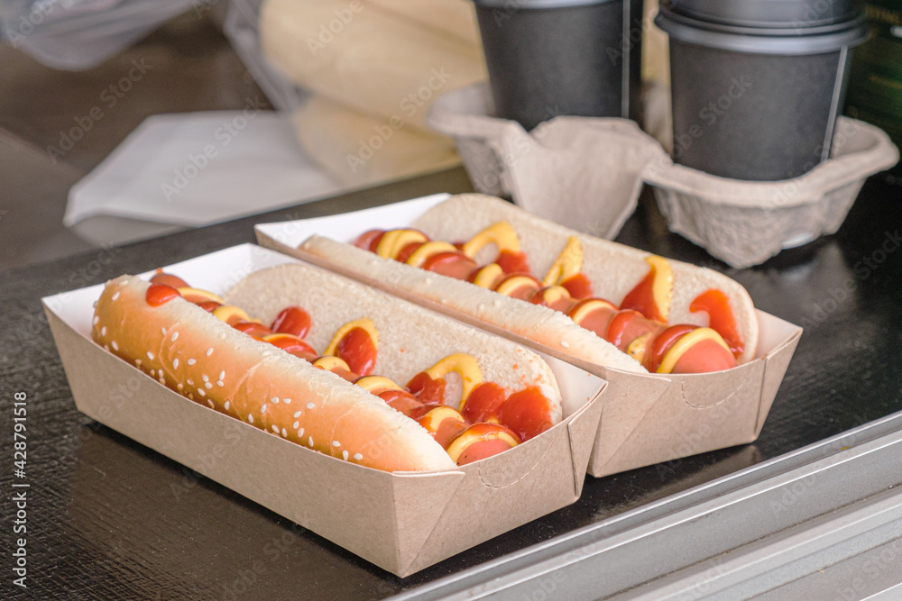 Two hot dogs in a cardboard box and two cardboard cups of coffee on the ...