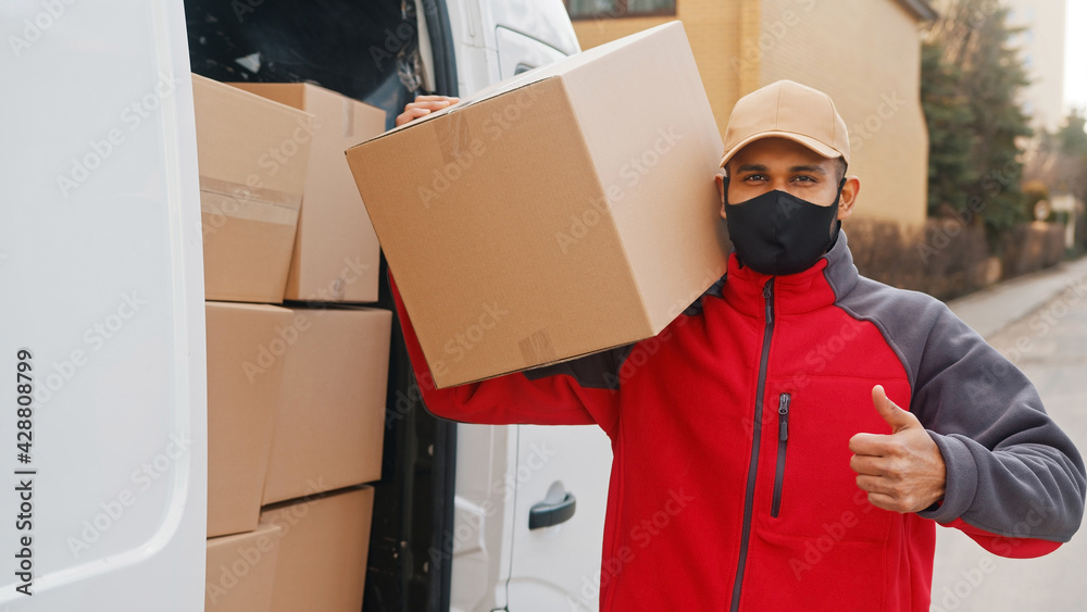Adult man standing outdoors next to van and holding cardboard box on ...