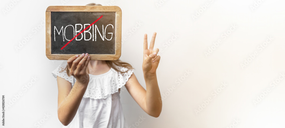 Young girl with school blackboard with the word MOBBING shows peace ...