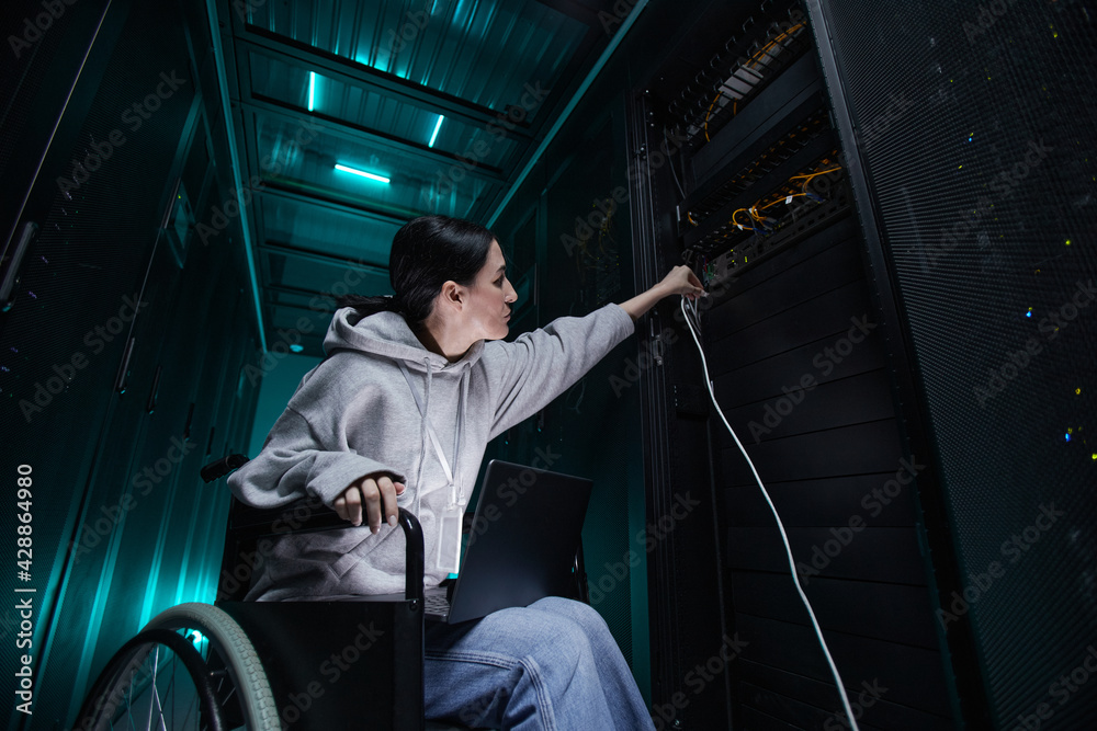 Low angle portrait of disabled woman in wheelchair working with ...