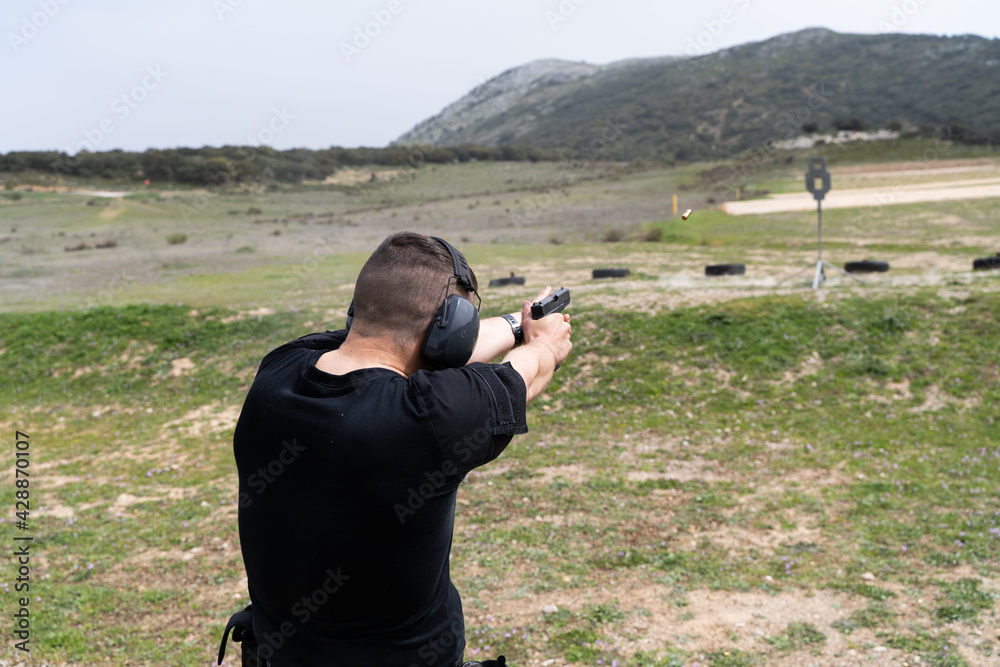 Hombre disparando una pistola hacia una silueta metálica, deporte IPSC ...
