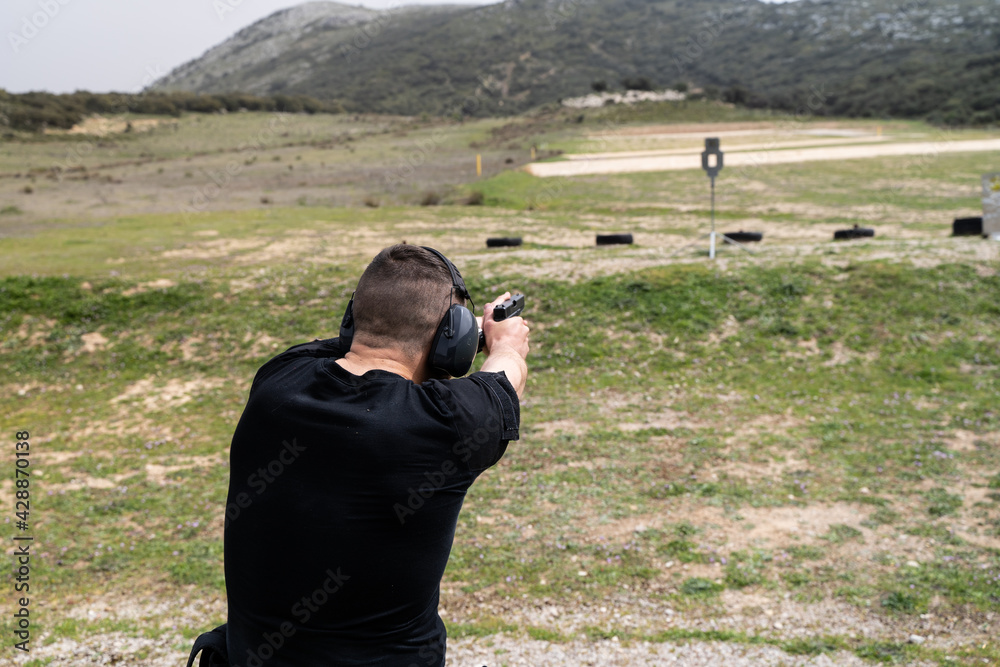 Hombre disparando una pistola hacia una silueta metálica, deporte IPSC ...