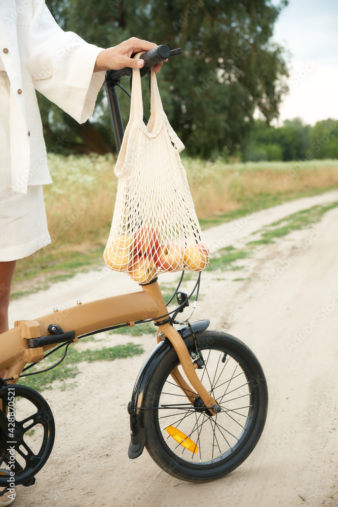 String bag with apples weighs on the handlebars of a folding bicycle ...