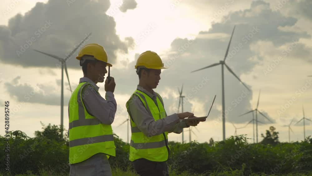Teamwork of Asian windmill engineer group, worker working, using a computer laptop on site at ...