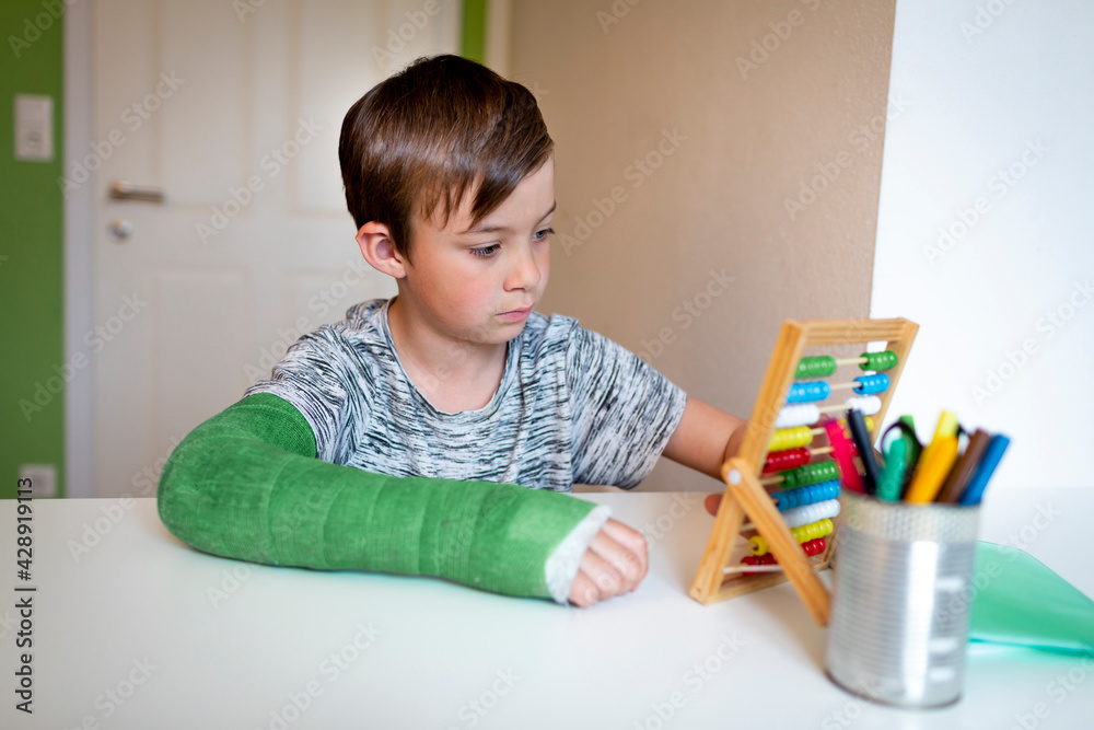 cool boy with green arm cast sits in his room and learns with slide ...