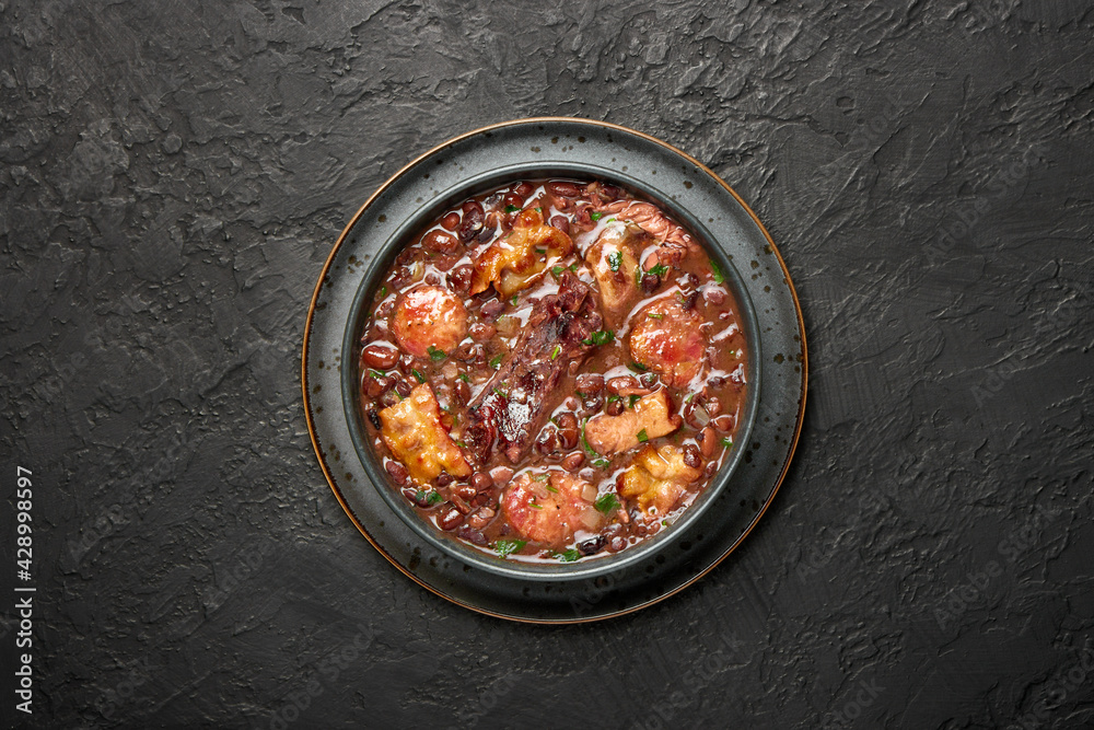 Feijoada in black bowl on dark slate table top. Brazilian and ...