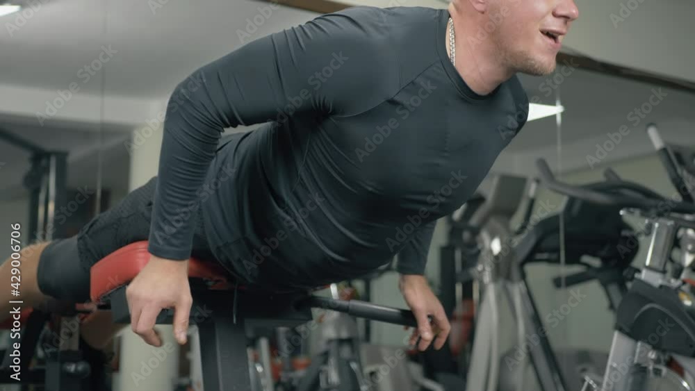 Bodybuilder performs a back-extension exercise on a roman chair. A ...