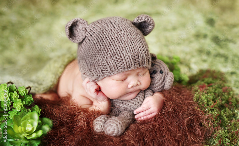 Baby huging a little bear doll. Newborn wearing a brown bear hat with ...