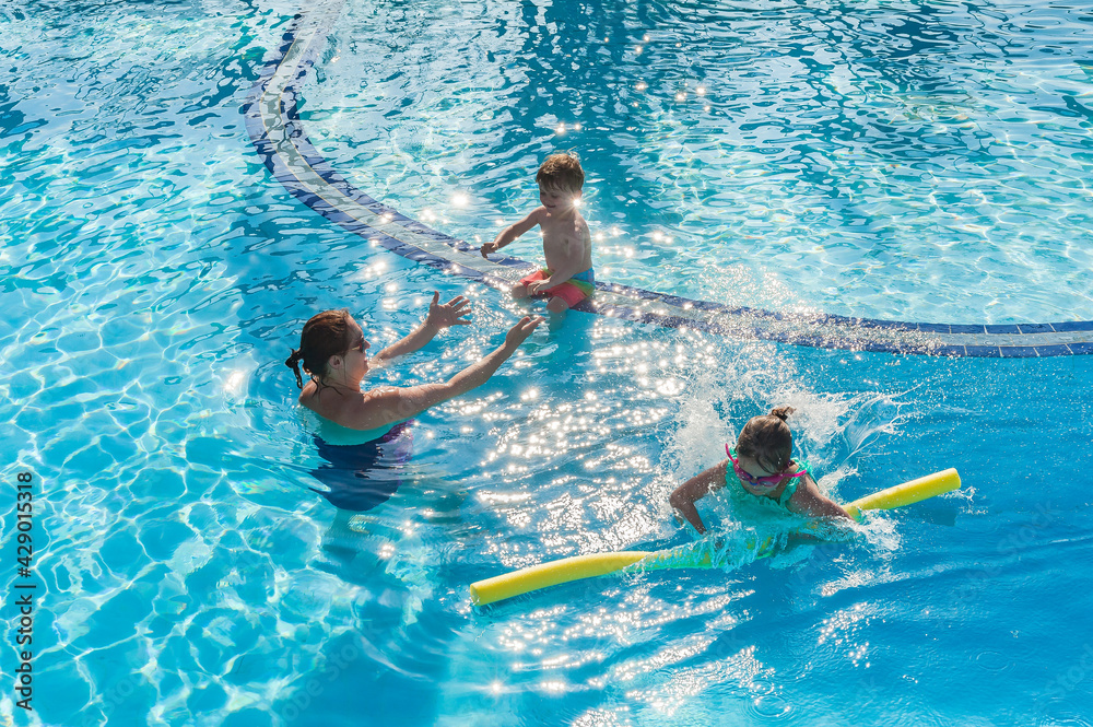 Family relaxing and having fun while playing together in swimming pool ...
