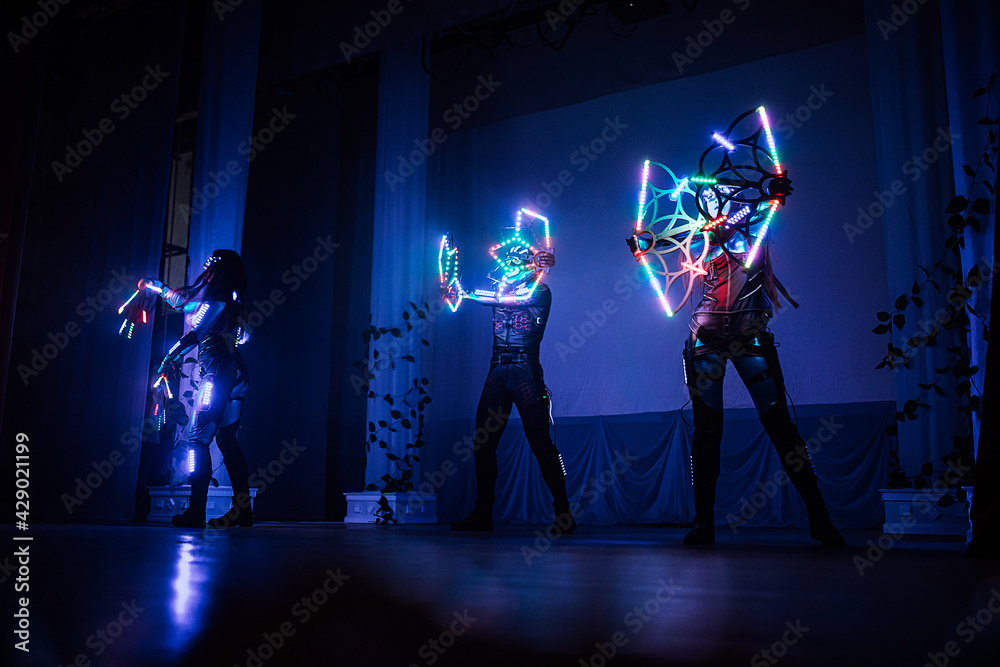 digital art dance show in LED costumes. neon fans in the hands of ...
