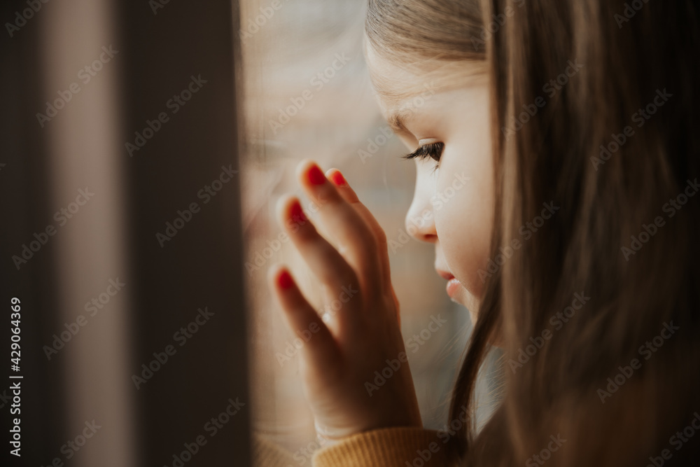 little girl looks out the window of a high-rise building in a sleeping ...