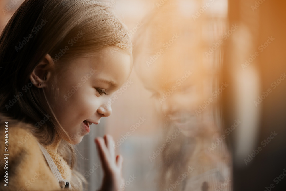 little girl looks out the window of a high-rise building in a sleeping ...