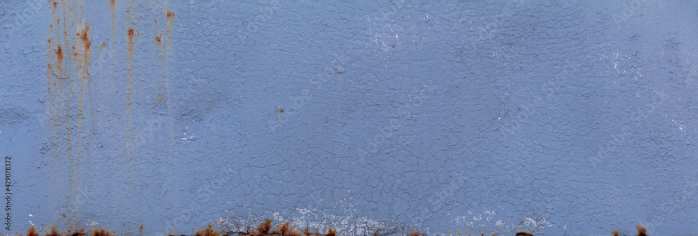 Blue uneven paint on the wall with traces and streaks of red rust ...
