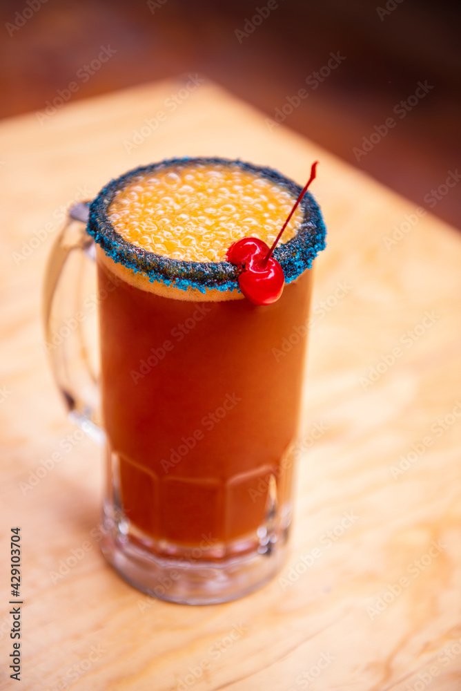 Michelada beer with tomato juice. Clamato with beer on wooden table ...