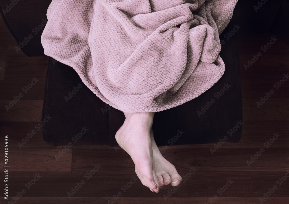Bare feet sticking out from under throw blanket on recliner foot rest ...