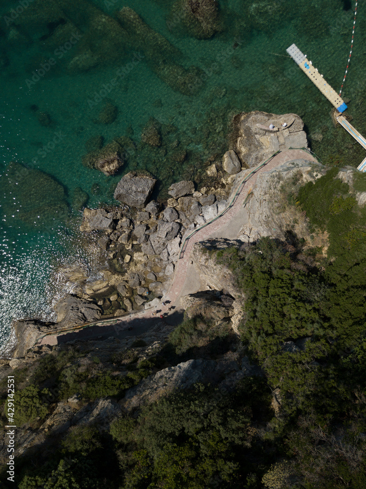 Aerial top down view of way path along stone cliff with green forest to ...