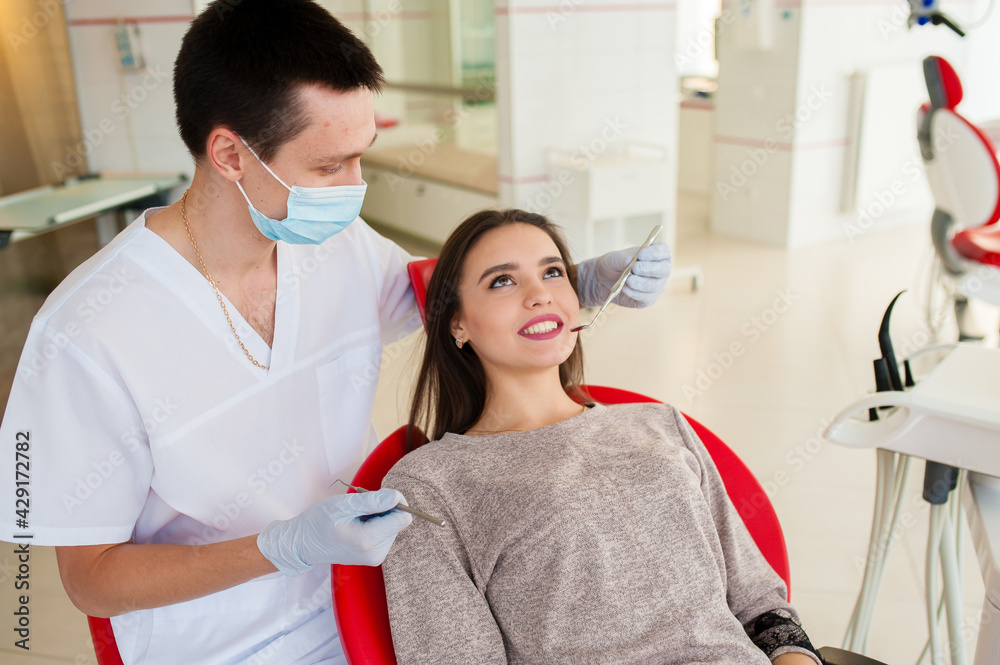 Doctor dentist treats teeth of a beautiful young girl patient. The girl ...