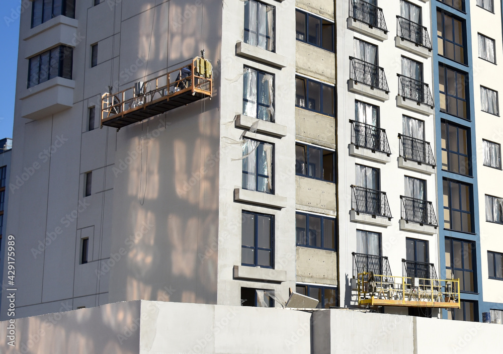 Suspended construction cradle on the background facade of the building ...