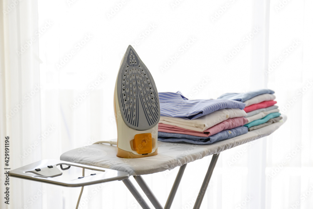 Fotka „Stack of clean freshly laundered clothes and electric iron on ...