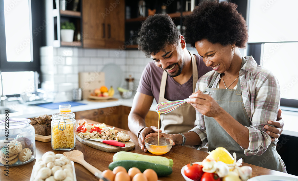 Beautiful young couple having fun and laughing while cooking in kitchen ...