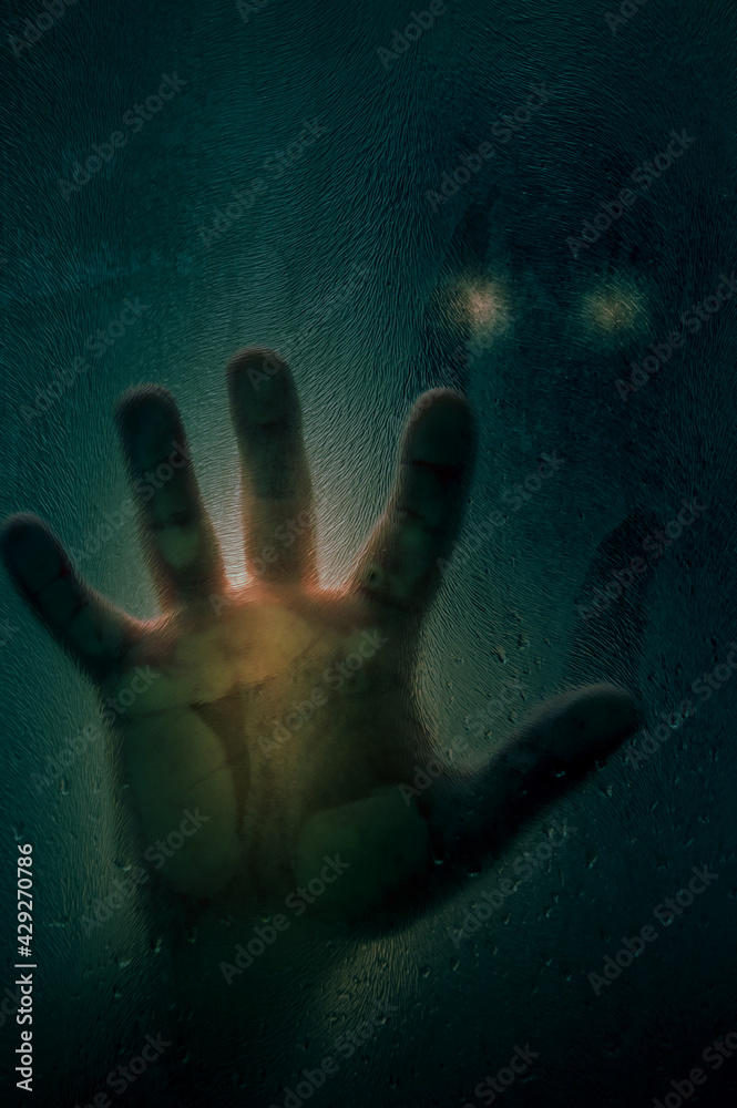 Horror scene of a man with hand against wet shower glass and dark ...