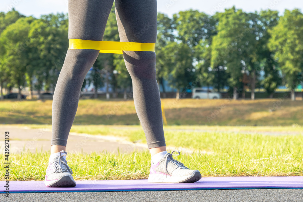 Close-up, a woman is engaged in an exercise with an elastic band while ...
