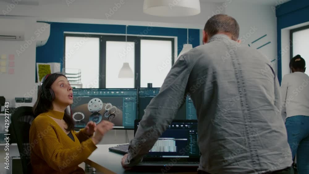 Teamwork sharing ideas about industrial project analysing 3D gears looking at computer with CAD ...