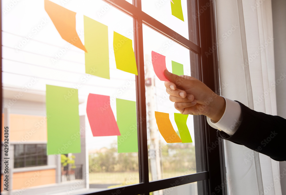 Business male hand put the Colorful of post on the wall. sticky note or ...