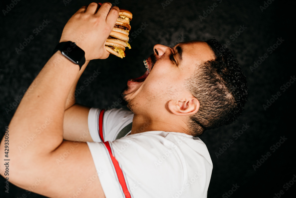 male model portrait on a black wall eating a burger Stock Photo | Adobe ...