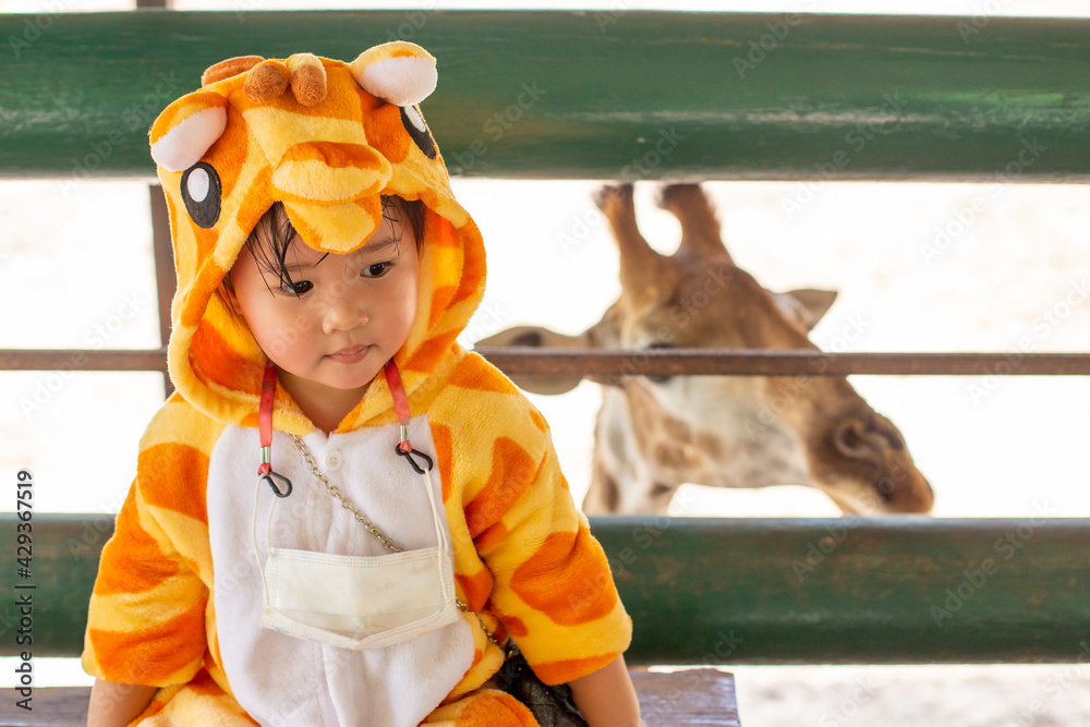 A cute Asian girl wearing a giraffe costume, Go on a trip in the zoo ...