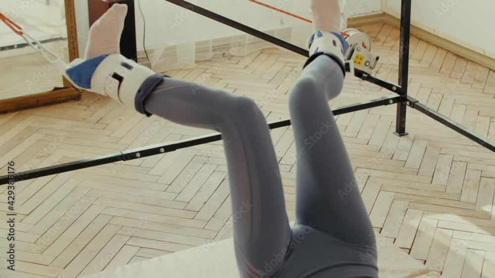 Female legs fixed on the trainer for stretching in gym. Stretch tendons ...