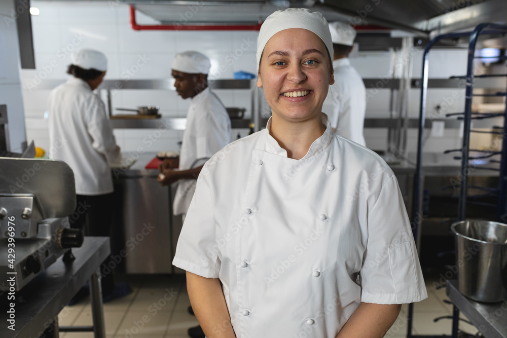 Portrait of caucasian female professional chef with diverse colleagues ...