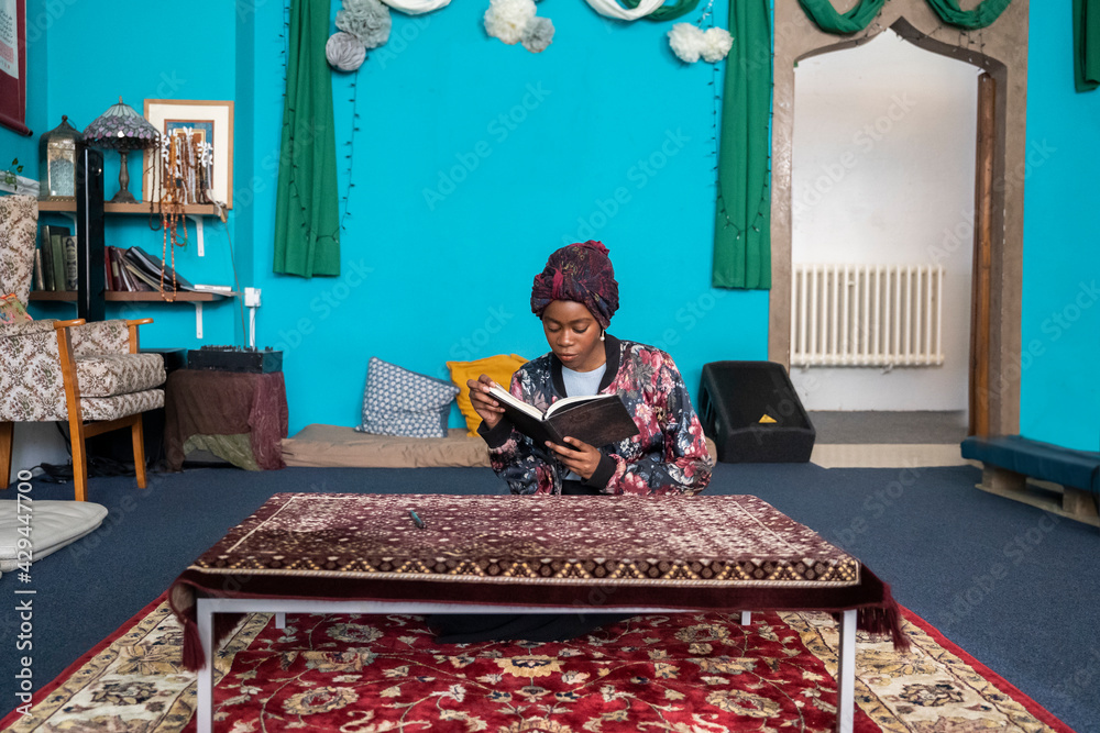 Black Muslim Woman studying in blue room Stock Photo | Adobe Stock