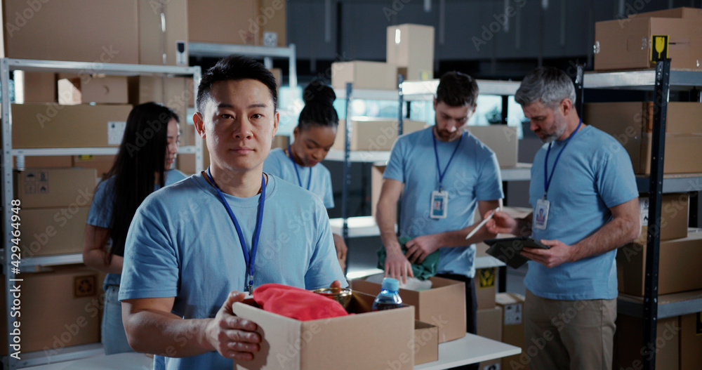 Multi-ethnic team of volunteers collaborating in workshop. Chinese male ...