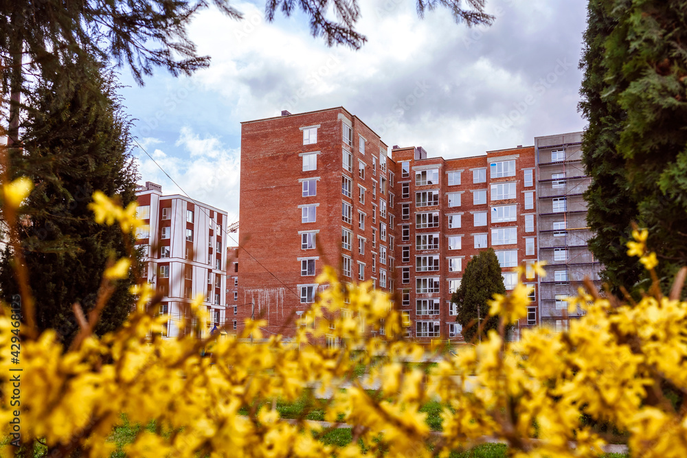 Multi-storey brick house under construction. Flowers and bushes on a ...