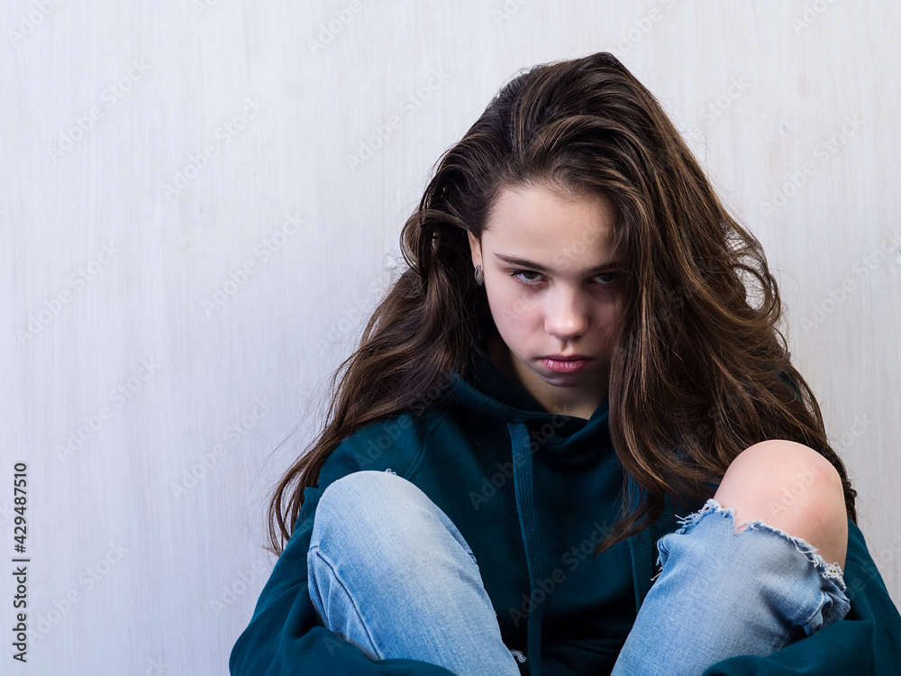 A teenage girl sits alone and is sad. Teenage psychology concept ...