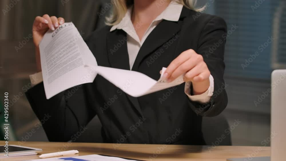 Businesswoman holds contract in hands and ripping it apart. Woman in ...