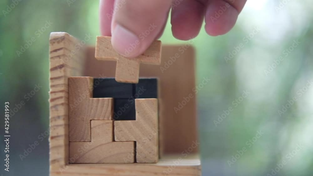 Man hand pick one of wooden brain teaser puzzle. metaphor to business ...