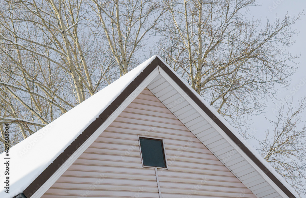 Triangular roof of a house in winter. A layer of white snow, plastic ...