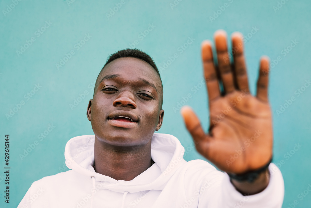 Portrait of young african black man against a green wall with white ...