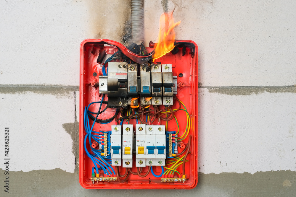 Burning switchboard from overload or short circuit on wall close-up ...