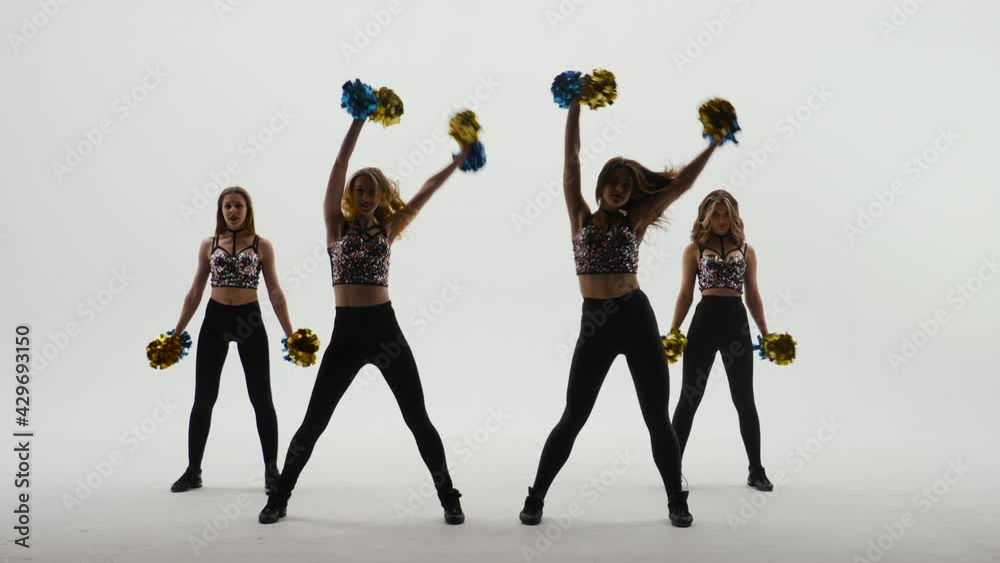 Group Of Athletic Cheerleaders In Silver Tops And Black Tight Leggings Are Dancing Cheering
