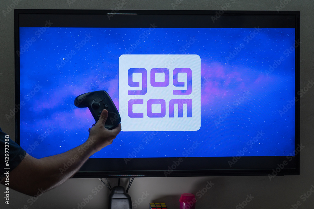 Man holding a controller in front of the loading screen for the GOG ...