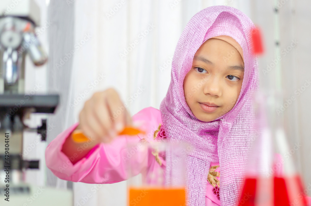 Muslim girl in elementary school in a science lab experiment, Islamic ...