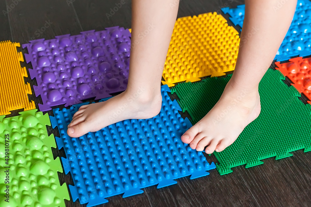 The legs of a small child on orthopedic mats. Bright surfaces for ...