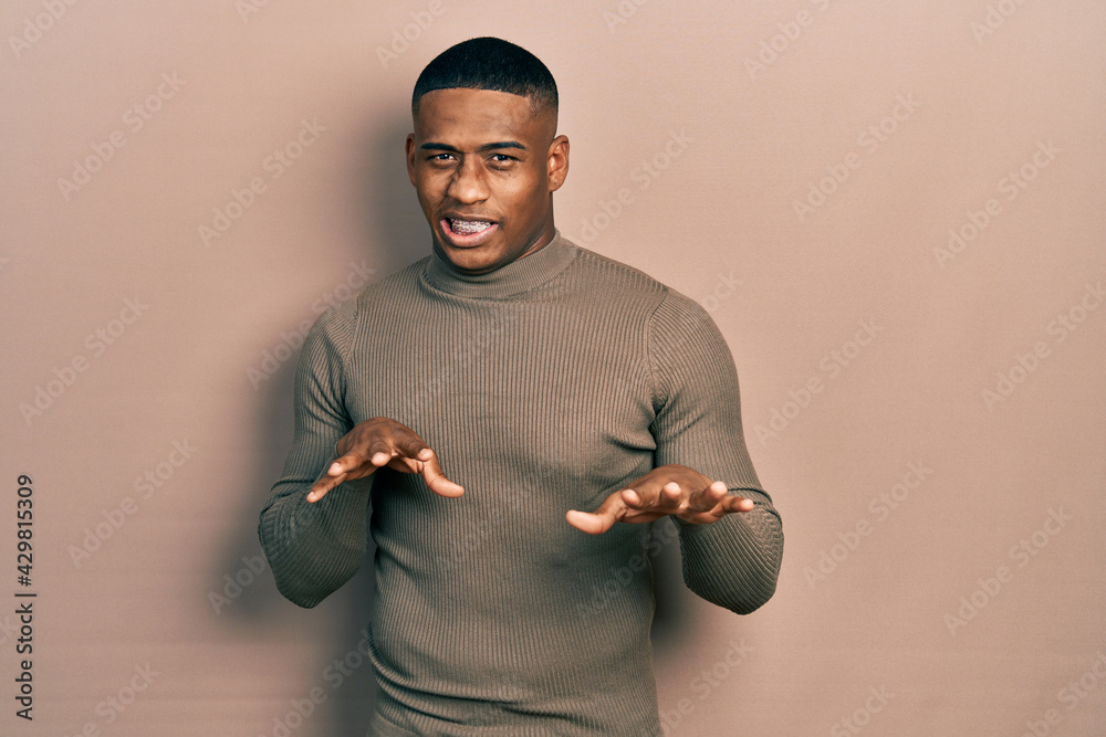 Young black man wearing casual turtleneck sweater disgusted expression ...
